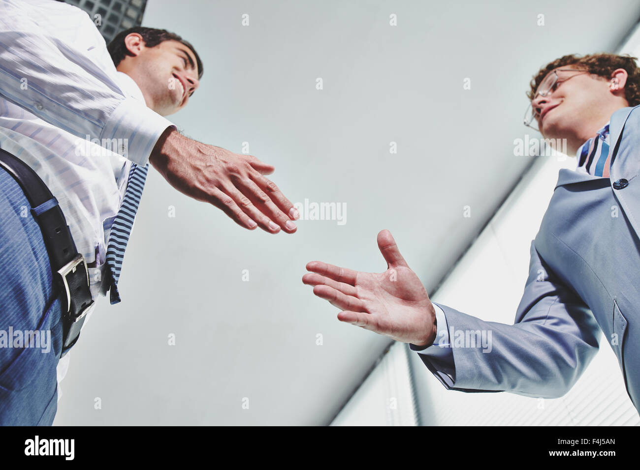 Two young businessmen greeting one another by handshake Stock Photo - Alamy