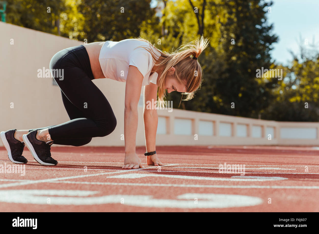 Portrait of a female runner in start position at outdoor stadium Stock ...