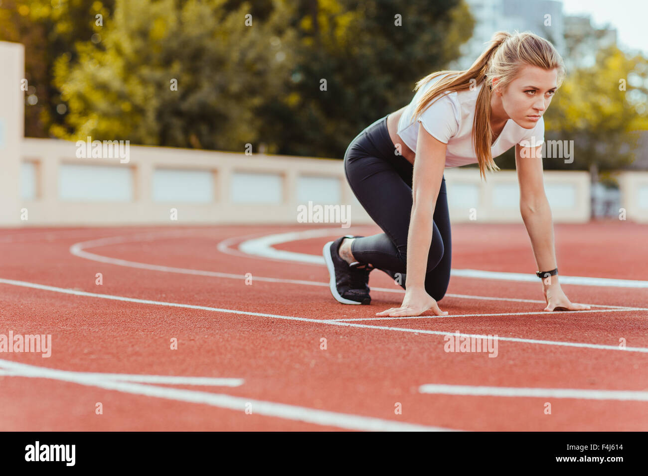 Portrait of a sports woman in star position for run on outdoor stadium ...