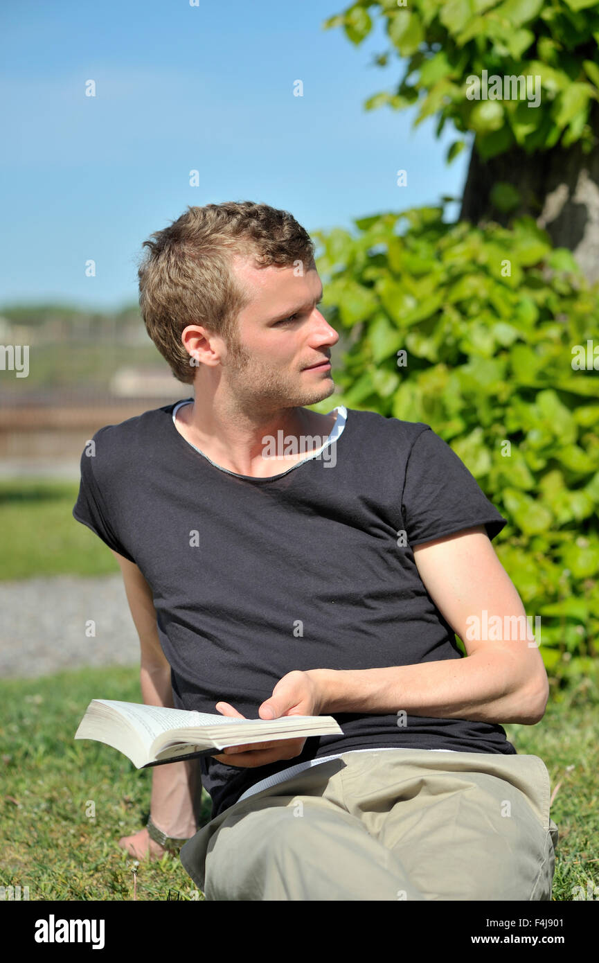 Young man reading by a tree, Sweden Stock Photo - Alamy