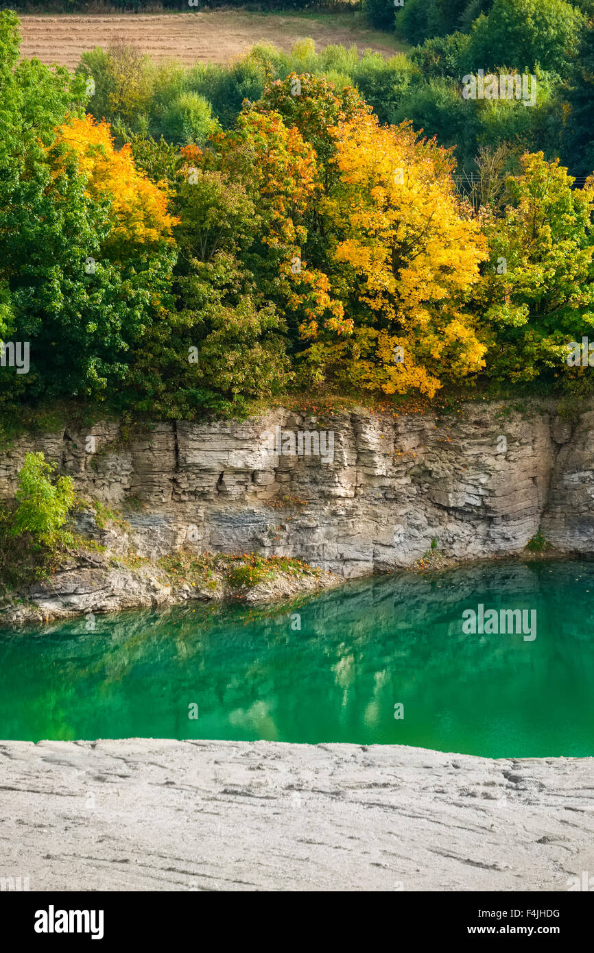 Autumn trees along a limestone cliff above the lagoon at Lea Quarry on ...