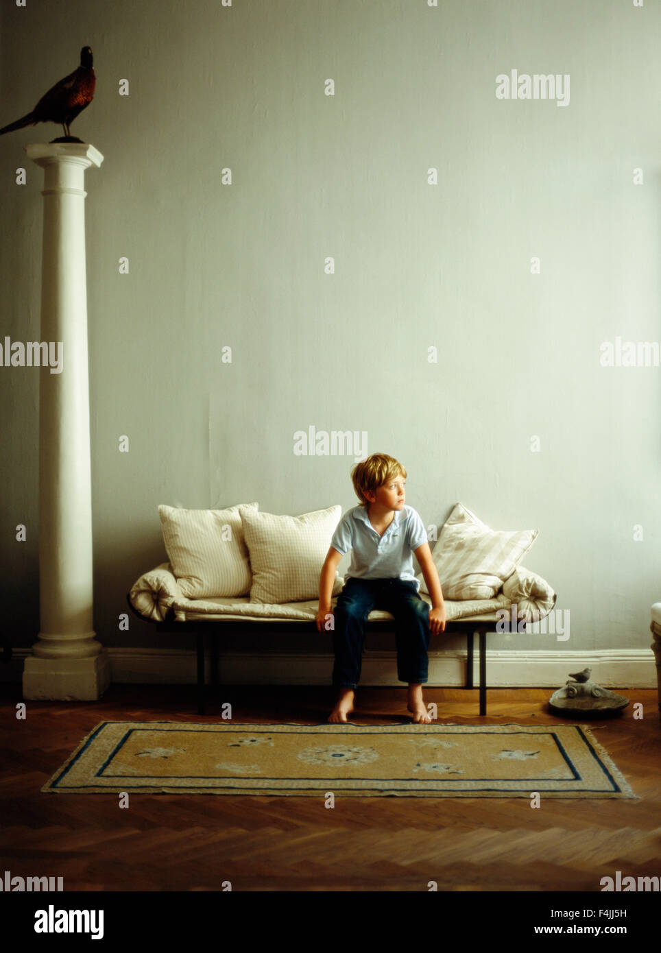 Boy sitting on sofa in fashionable room Stock Photo - Alamy