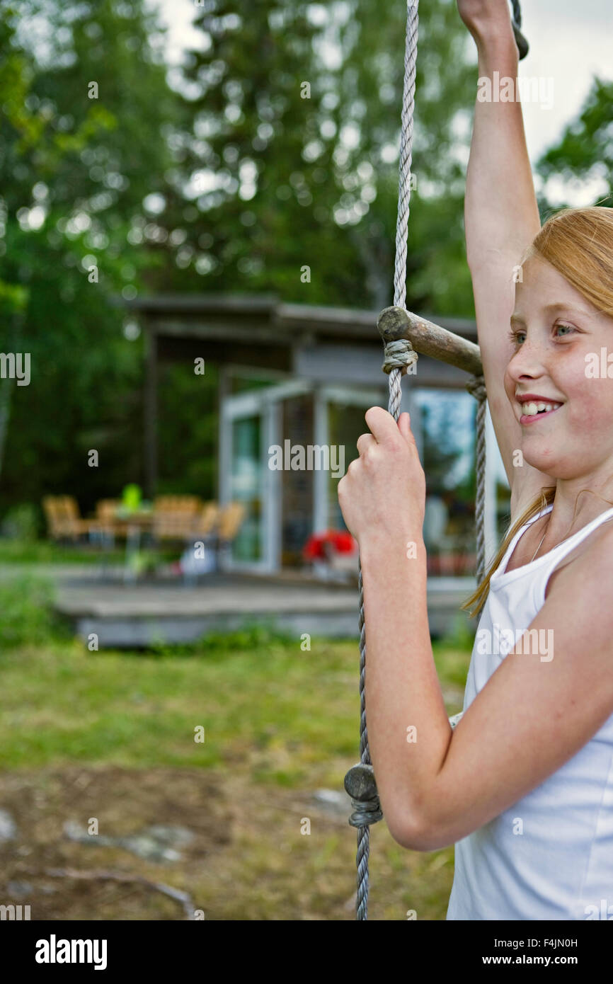 Sweden, girl (12-13) hanging on rope ladder Stock Photo - Alamy