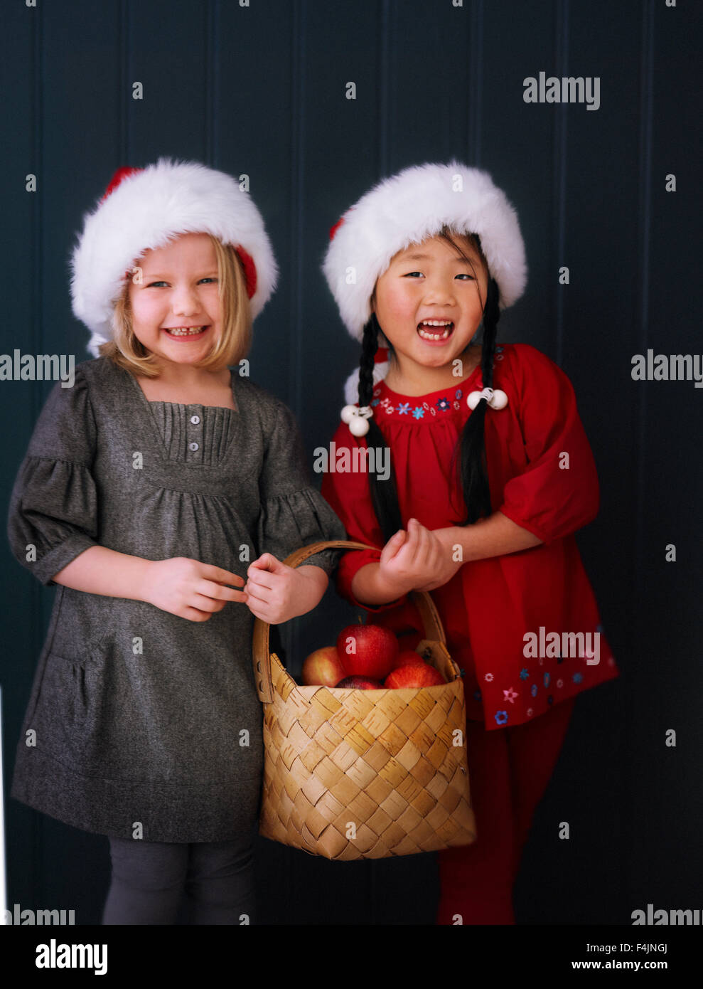 Sweden, Stockholm two girls wearing santa hats and holding basket with ...