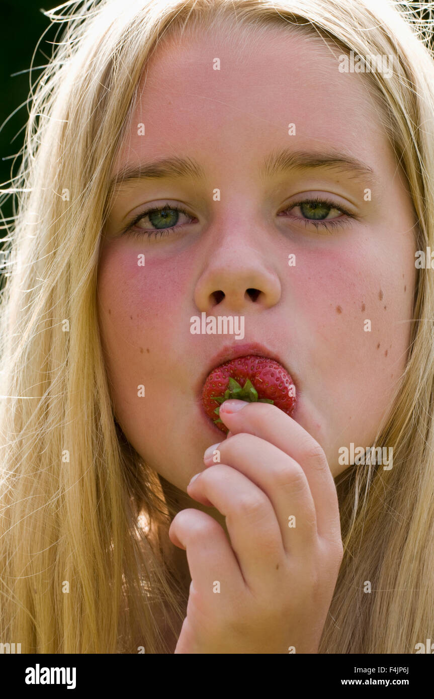 Portrait of girl eating strawberry Stock Photo - Alamy