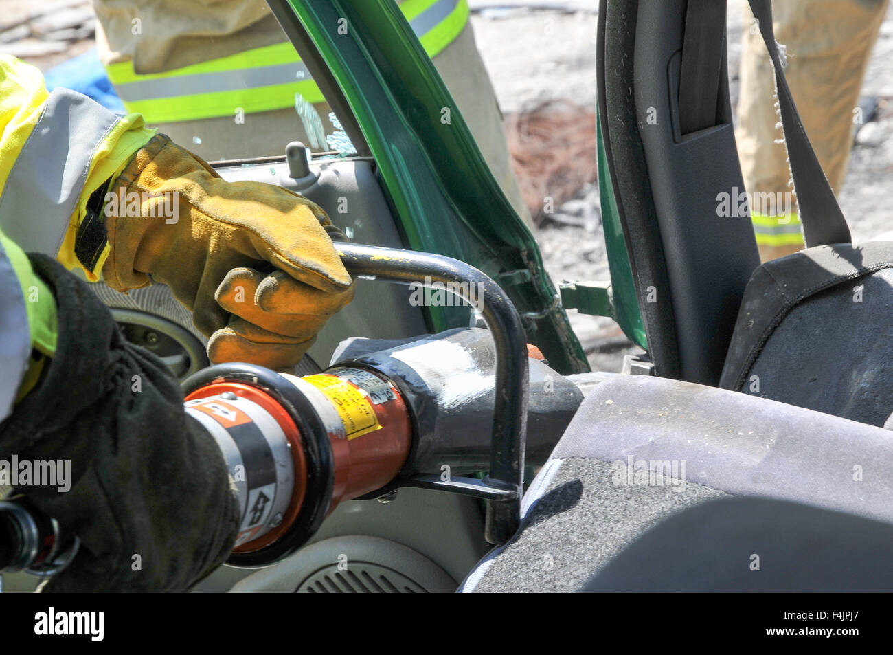 Firefighters use power tools to rescue trapped passengers from a car ...