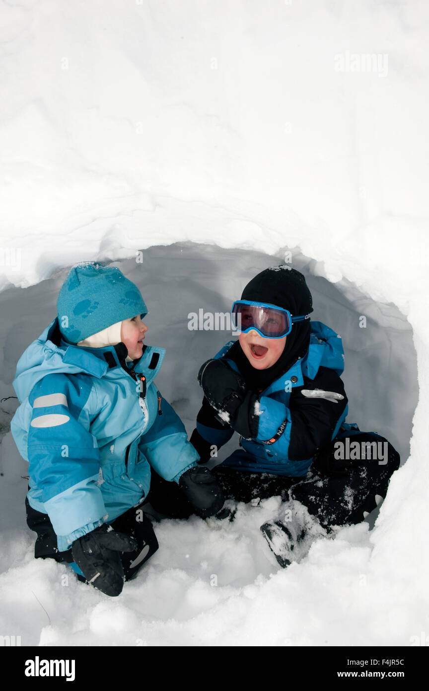 Boy and girl sitting in snow cave Stock Photo - Alamy