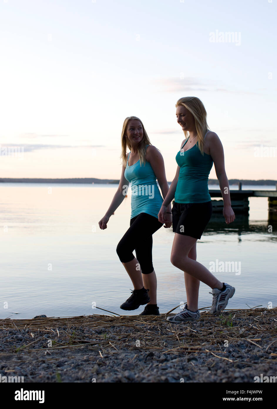 Two women walking by beach, side view Stock Photo - Alamy