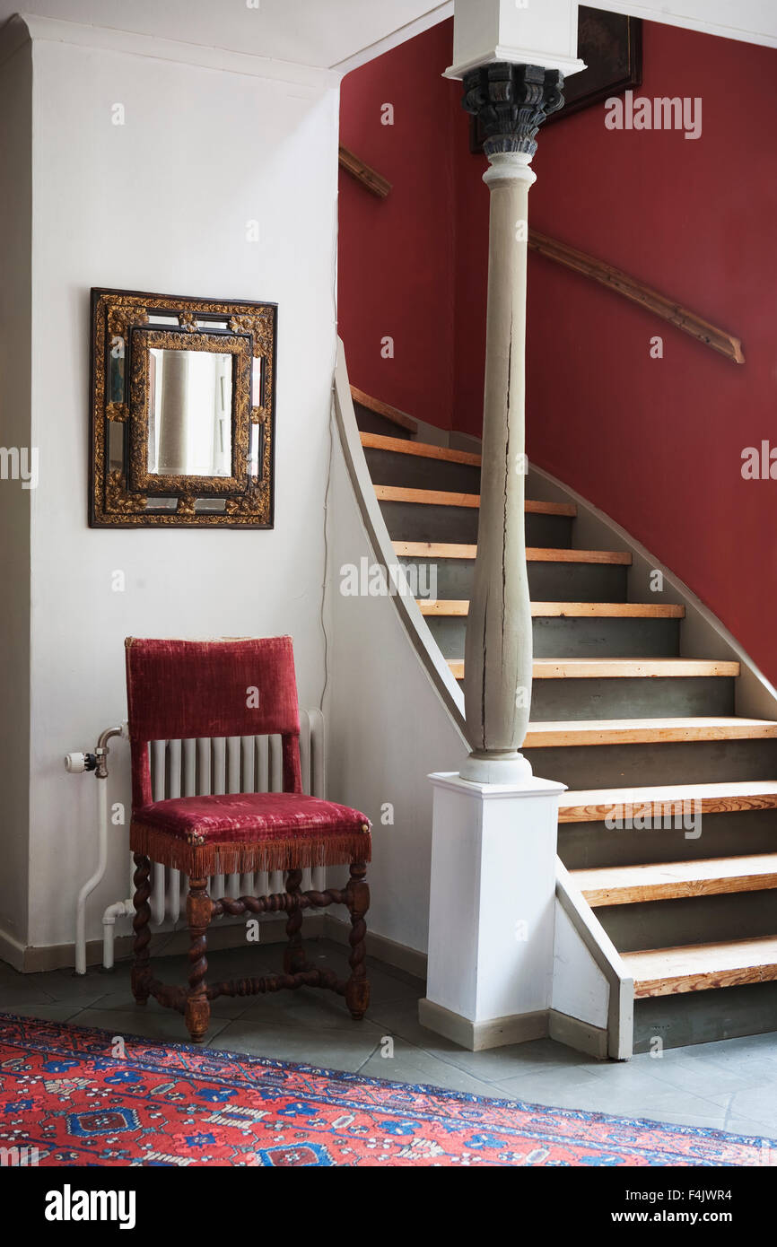 Chair and column beside wooden staircase Stock Photo - Alamy