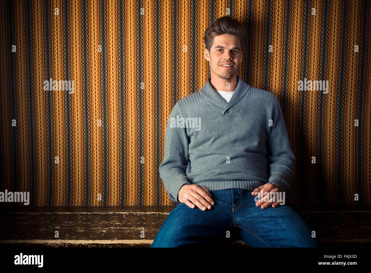 Young man sitting on bench, smiling, portrait Stock Photo - Alamy
