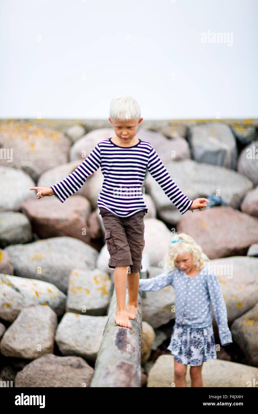 Boy balancing on log, girl in background Stock Photo - Alamy