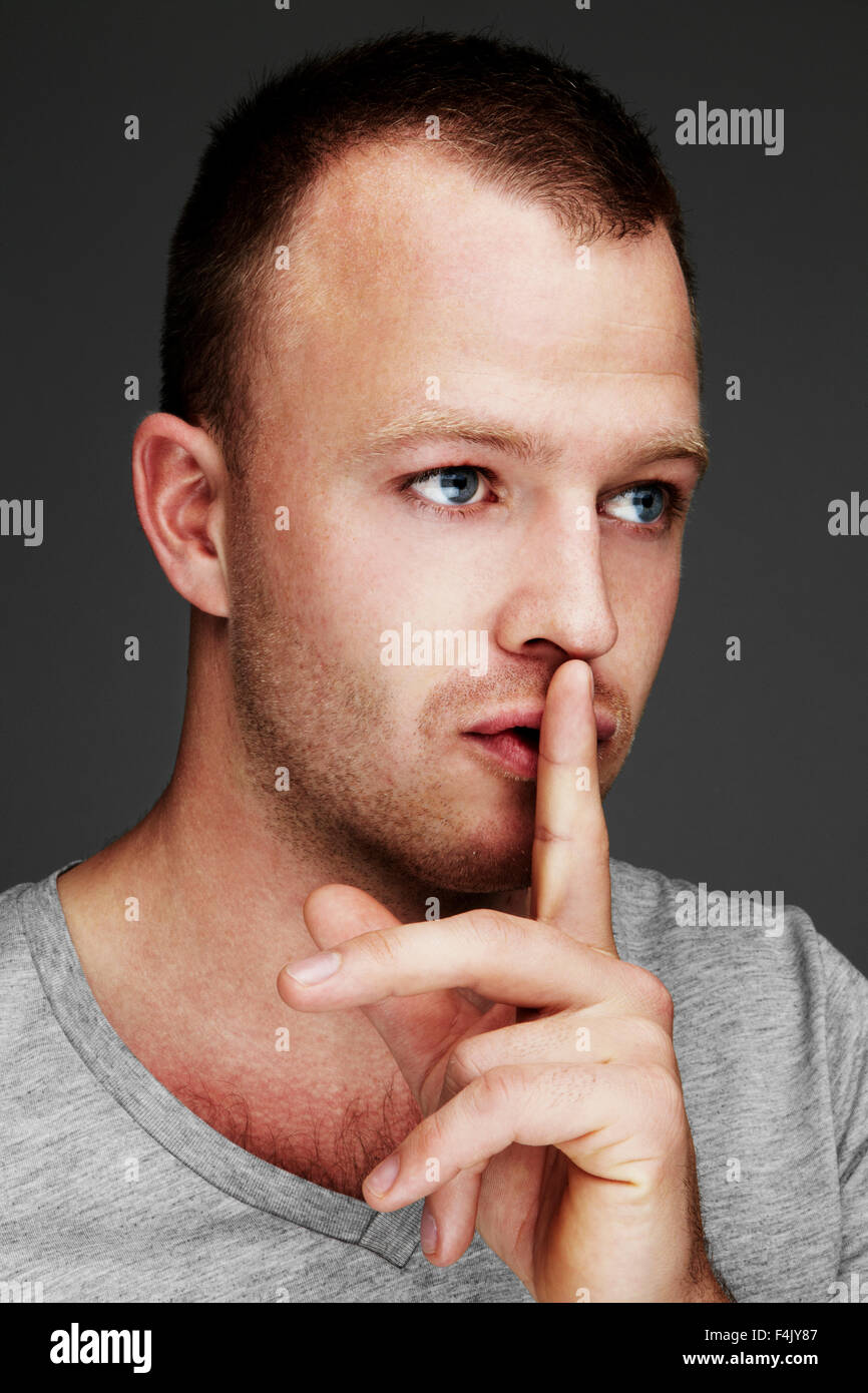 Studio portrait of man with finger on lips Stock Photo - Alamy