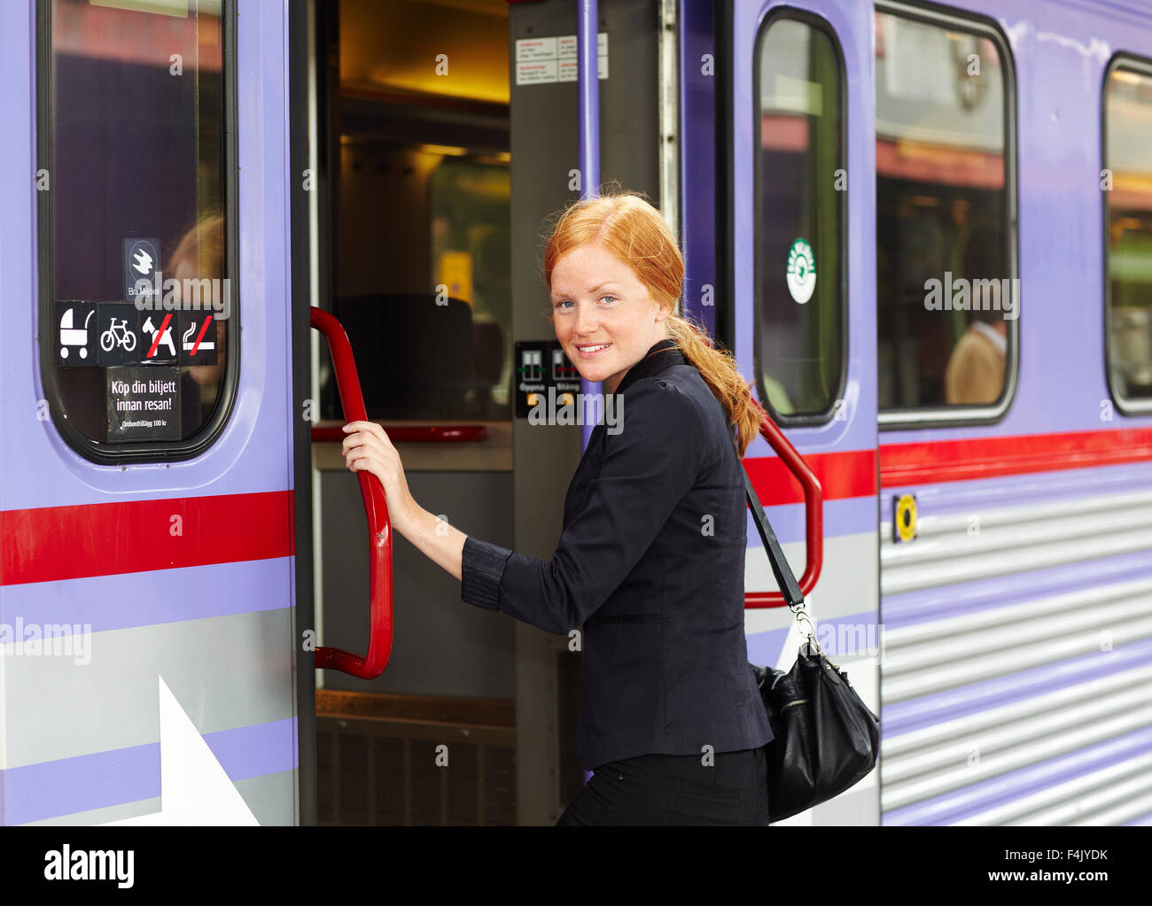 Smiling young woman boarding into train Stock Photo - Alamy
