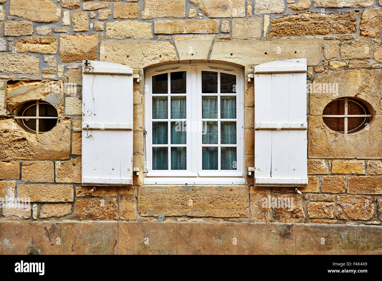 Window with white shutters in a stone building with two small windows ...