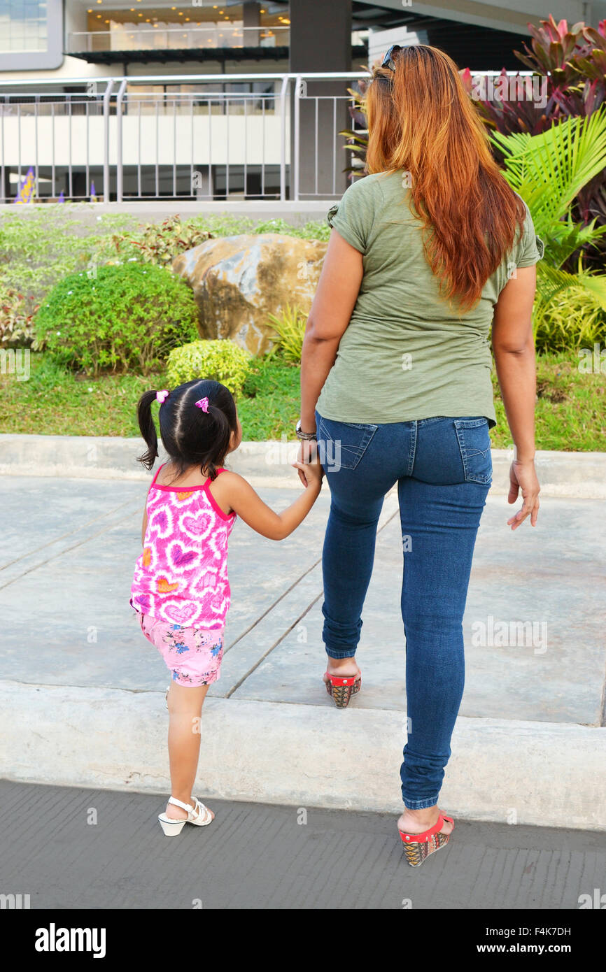 Little girl crossing the street hand in hand with her mother to go ...