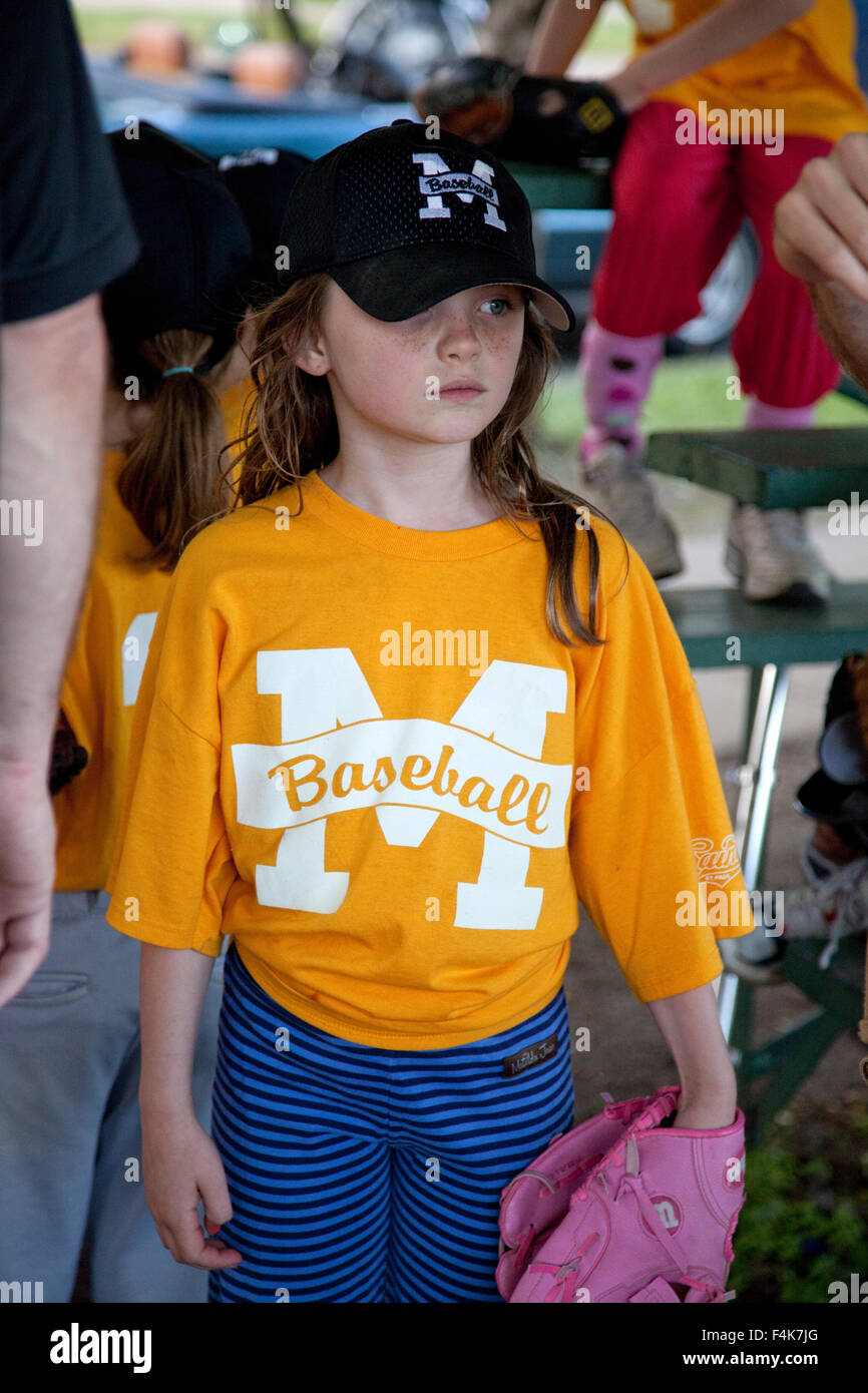 Young girl baseball player age 8 in uniform wearing pink mitt intently ...