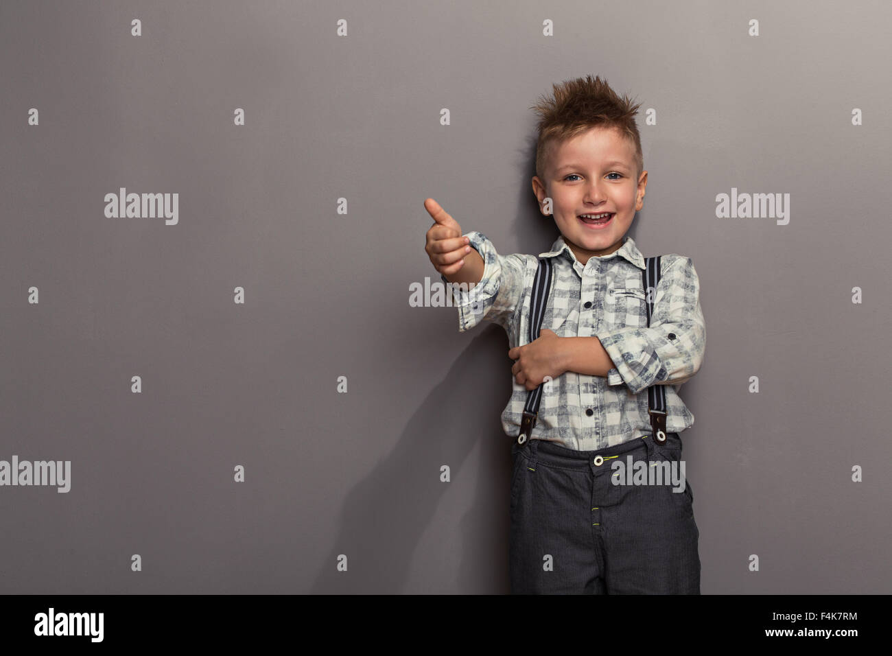 Fashion boy pointing down on grey background Stock Photo - Alamy