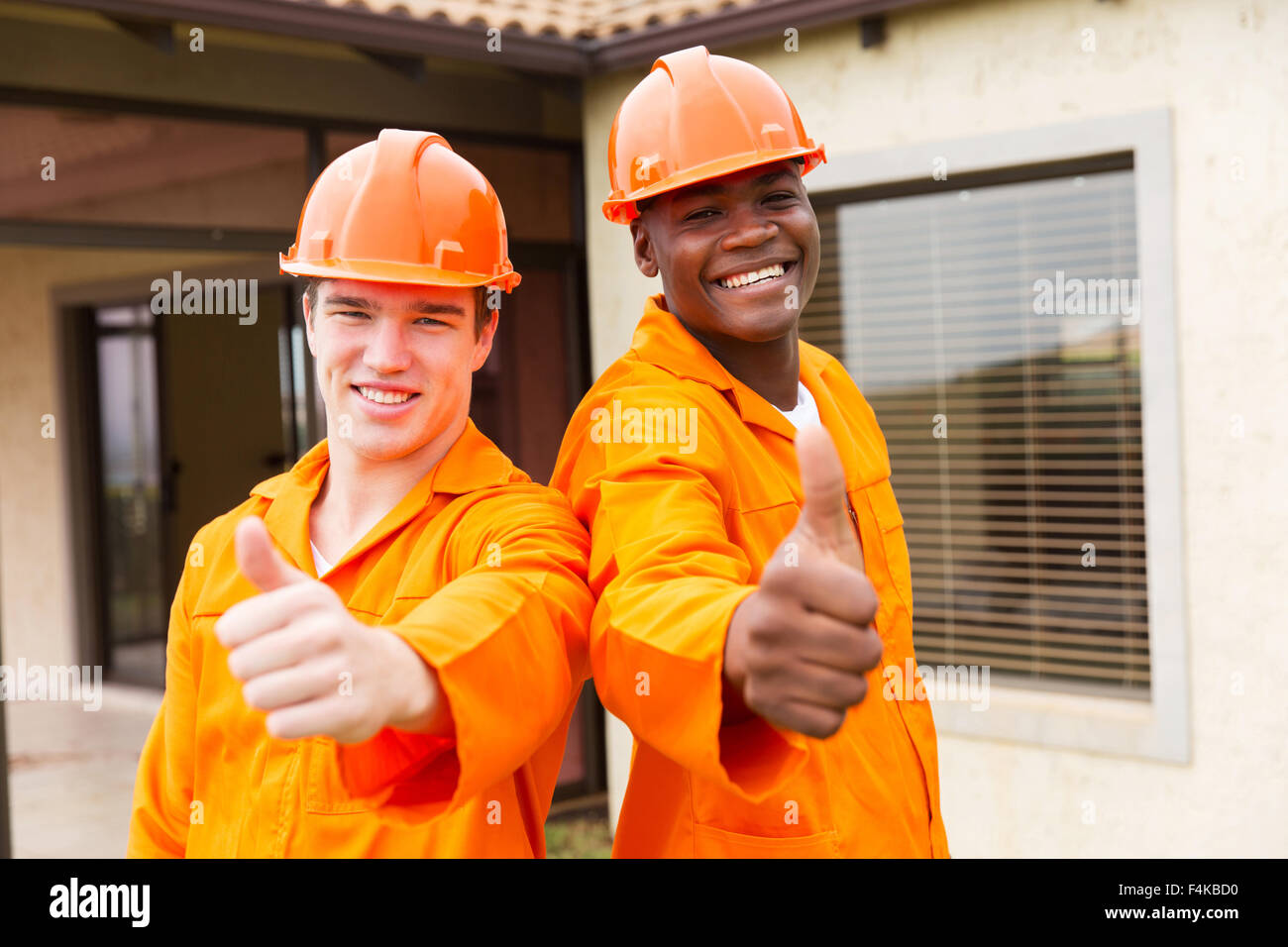 cheerful young construction workers thumbs up outside the house Stock ...