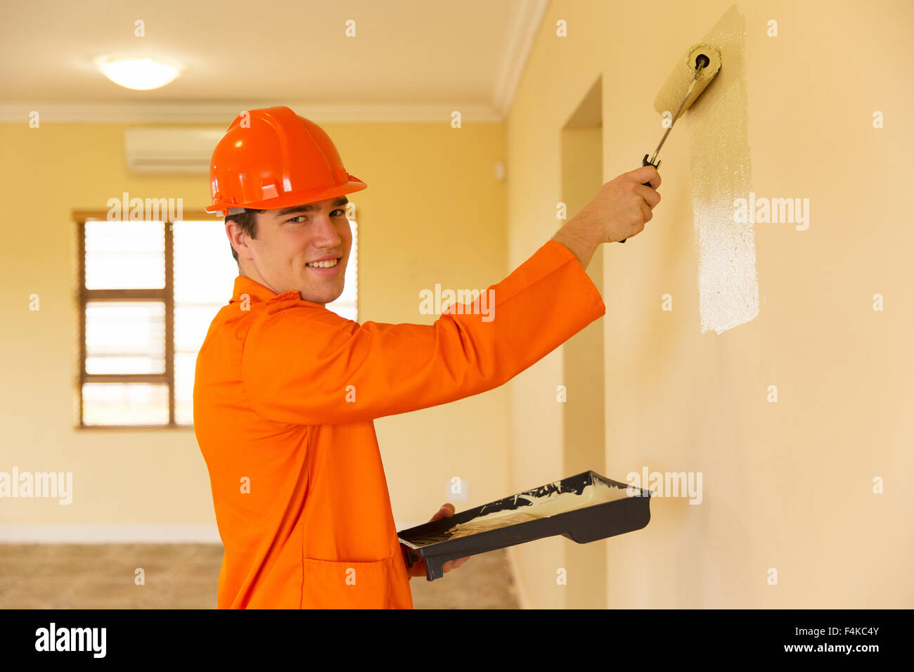 young contractor painting wall inside the house Stock Photo - Alamy