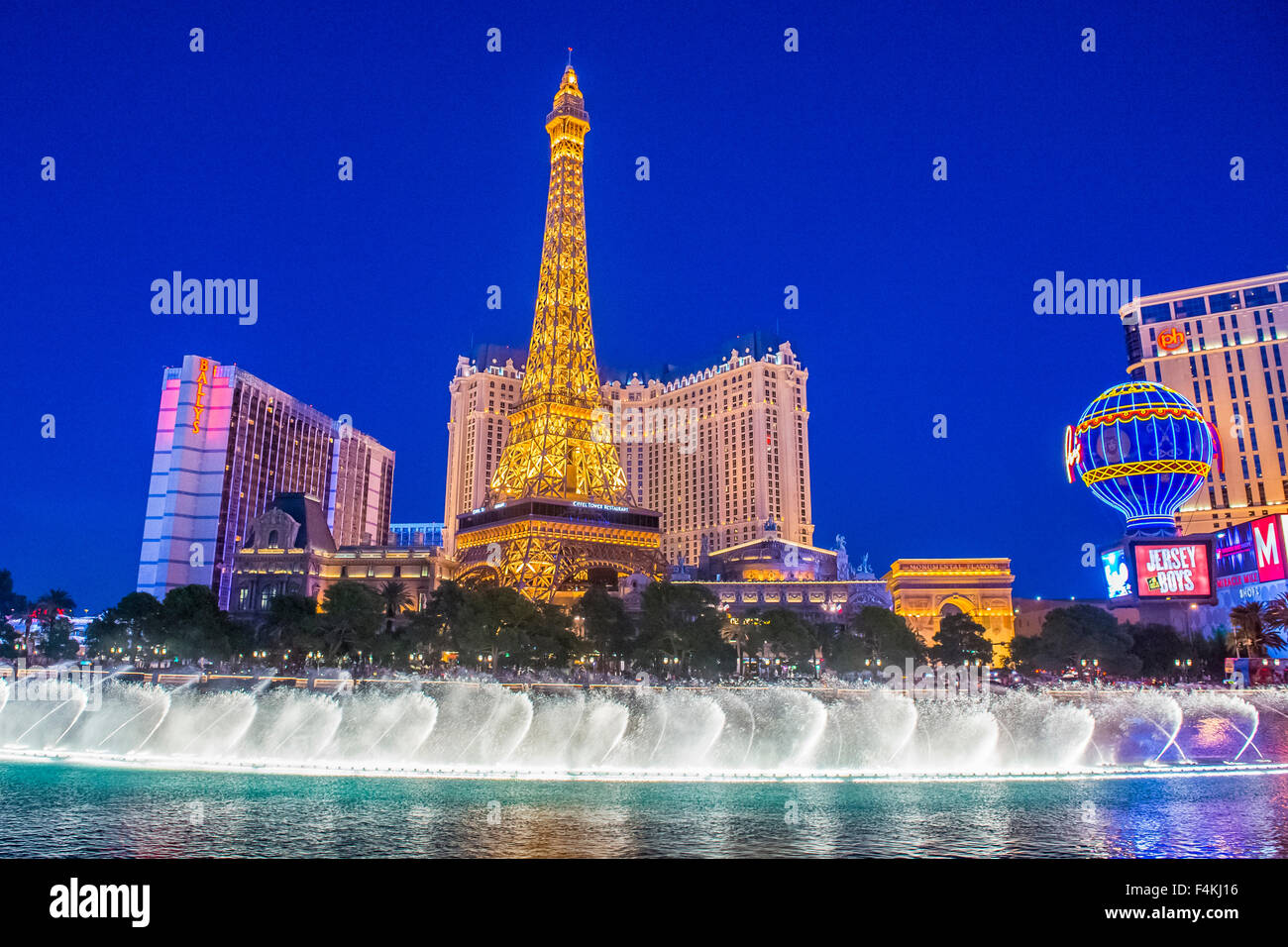 Night view of the dancing fountains of Bellagio and the Eiffel Tower replica of Paris hotel in ...