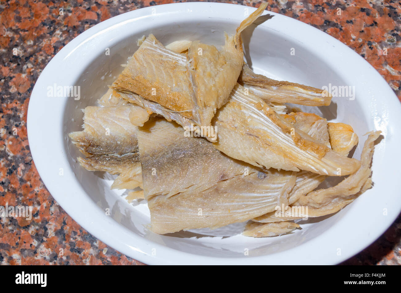 Pieces of dry fish lying on white plate drained in water, preparation ...