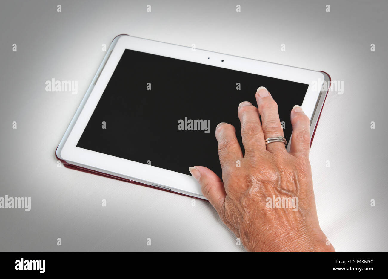 Hand of senior lady relaxing and reading the screen of her tablet ...