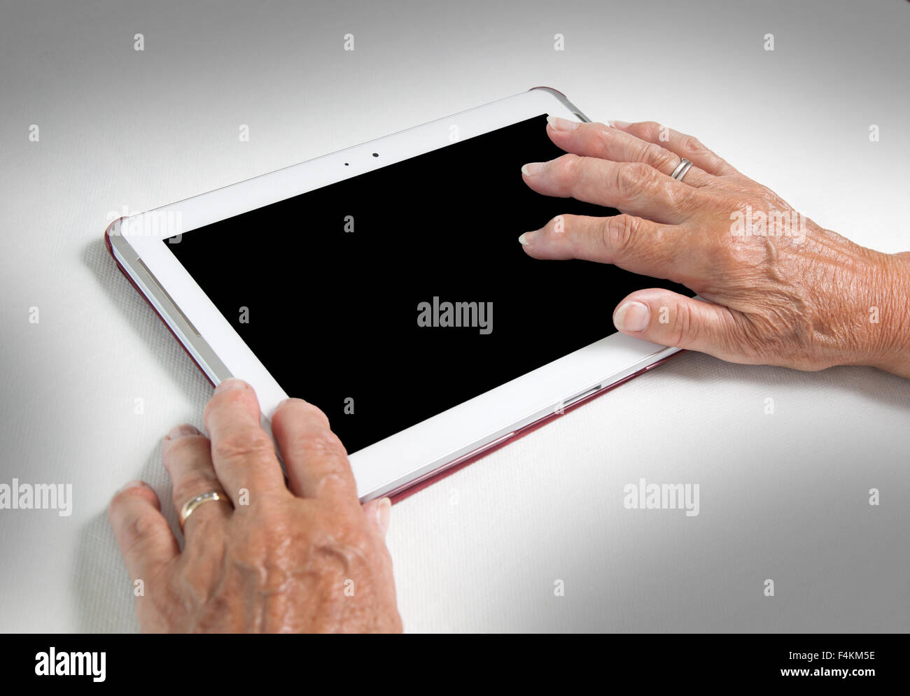 Hands of senior lady relaxing and reading the screen of her tablet ...