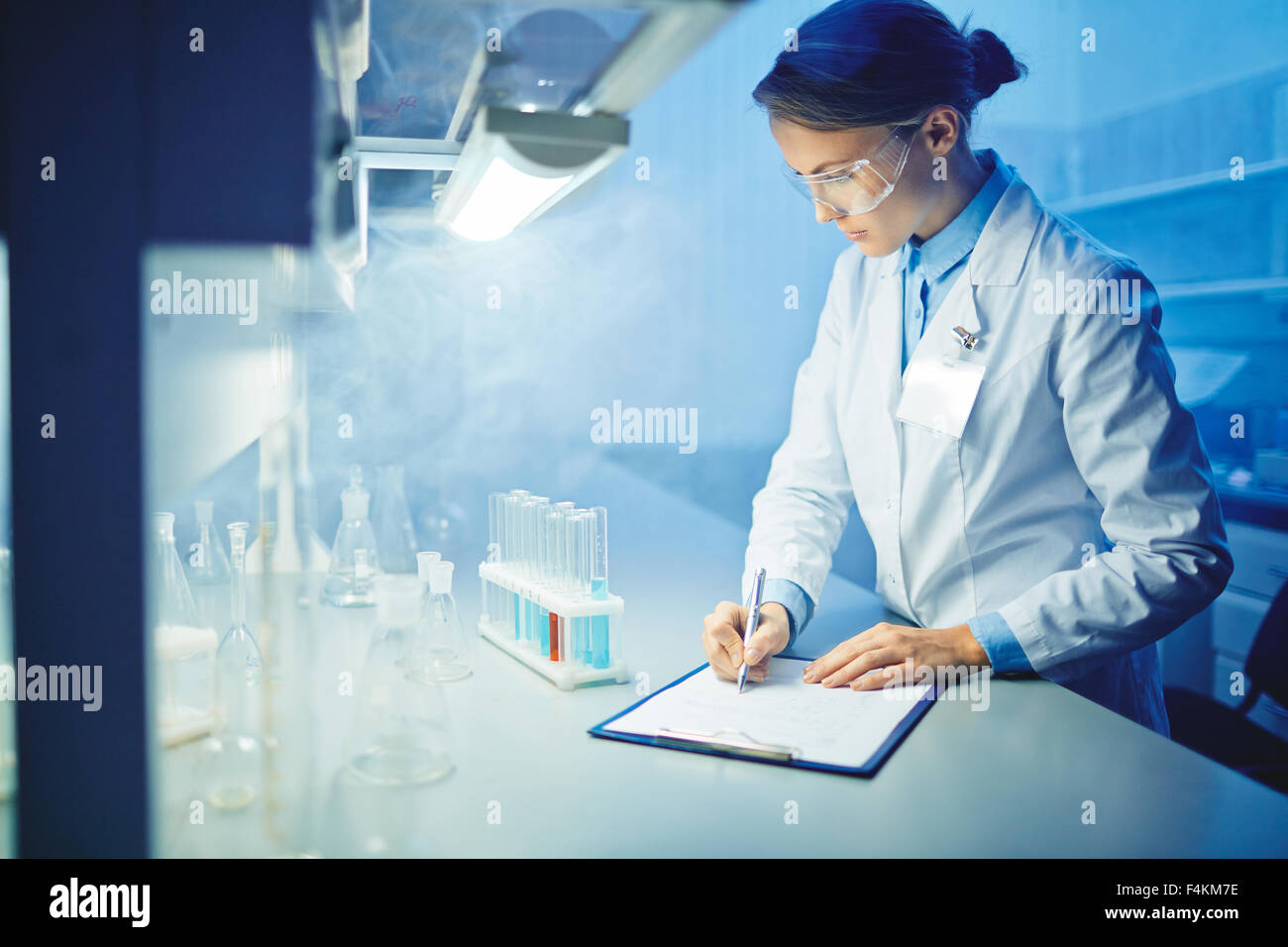 Female microbiologist learning characteristics of new substances in ...