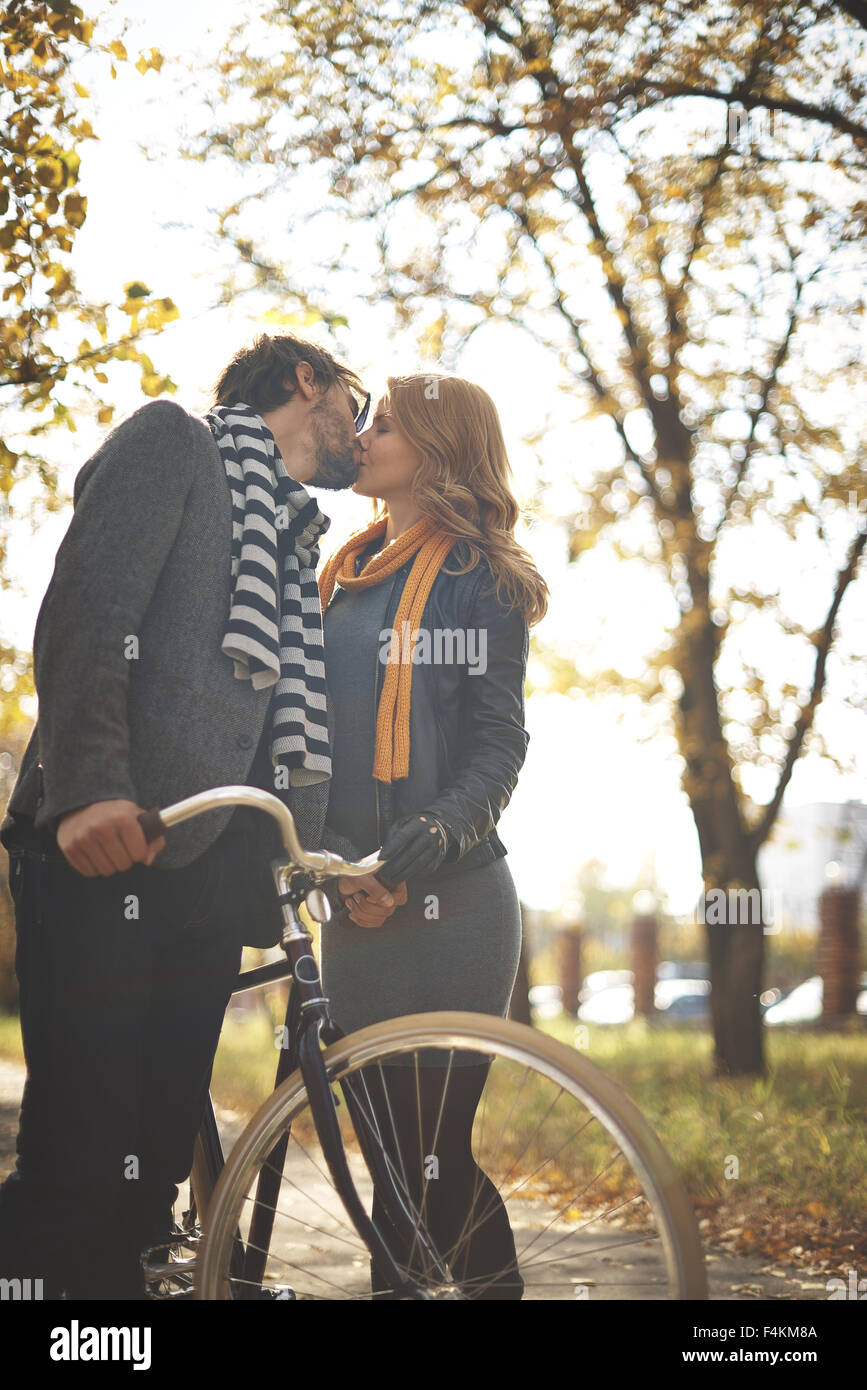 Amorous young couple with bicycle kissing in park Stock Photo - Alamy
