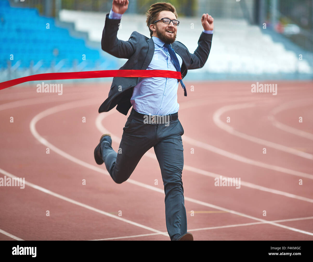 Winning businessman reaching finish ribbon at stadium Stock Photo - Alamy