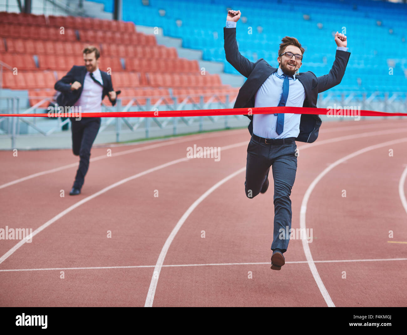 Ecstatic businessman touching red finish ribbon at stadium Stock Photo ...