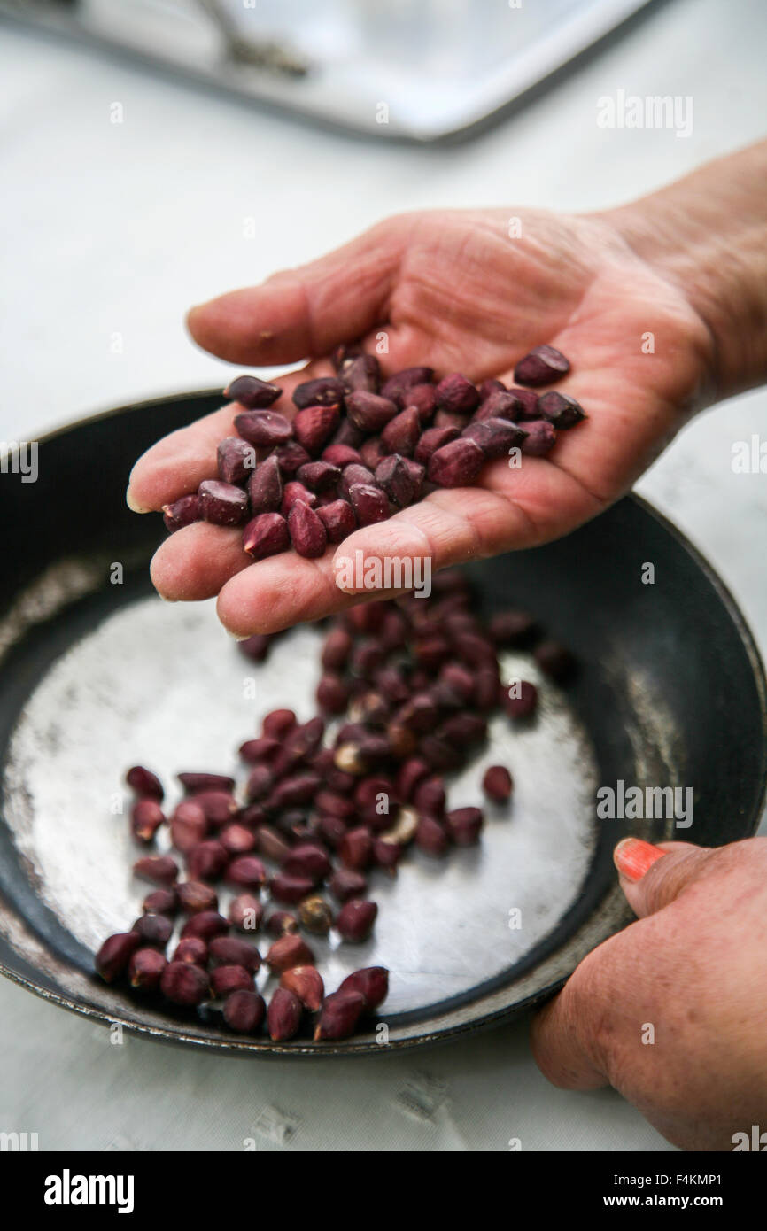 Hand holding up palm, black beans over frying pan with more of same ...