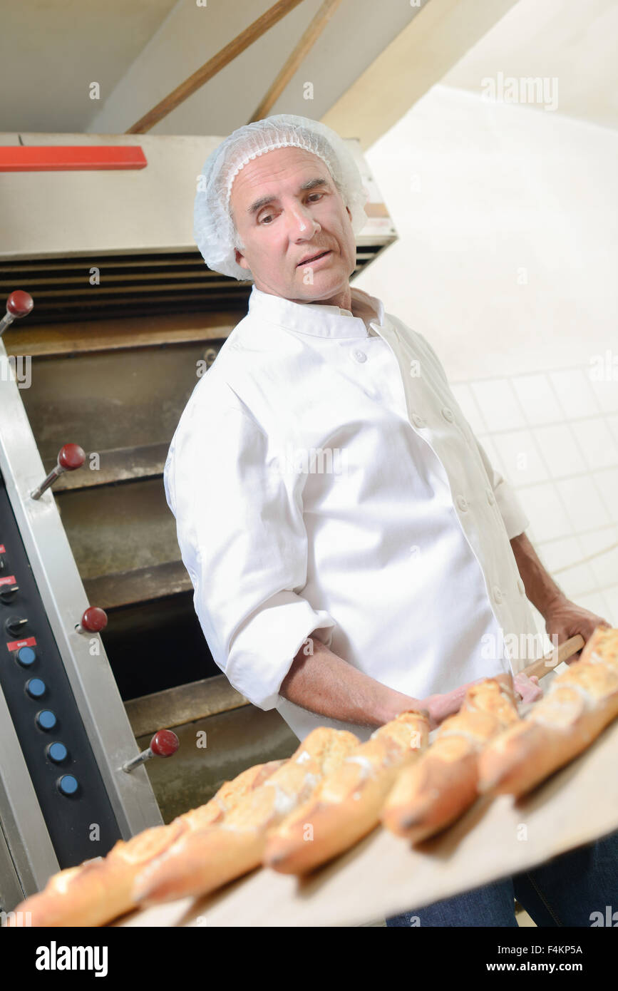 Baker removing bread from oven Stock Photo - Alamy