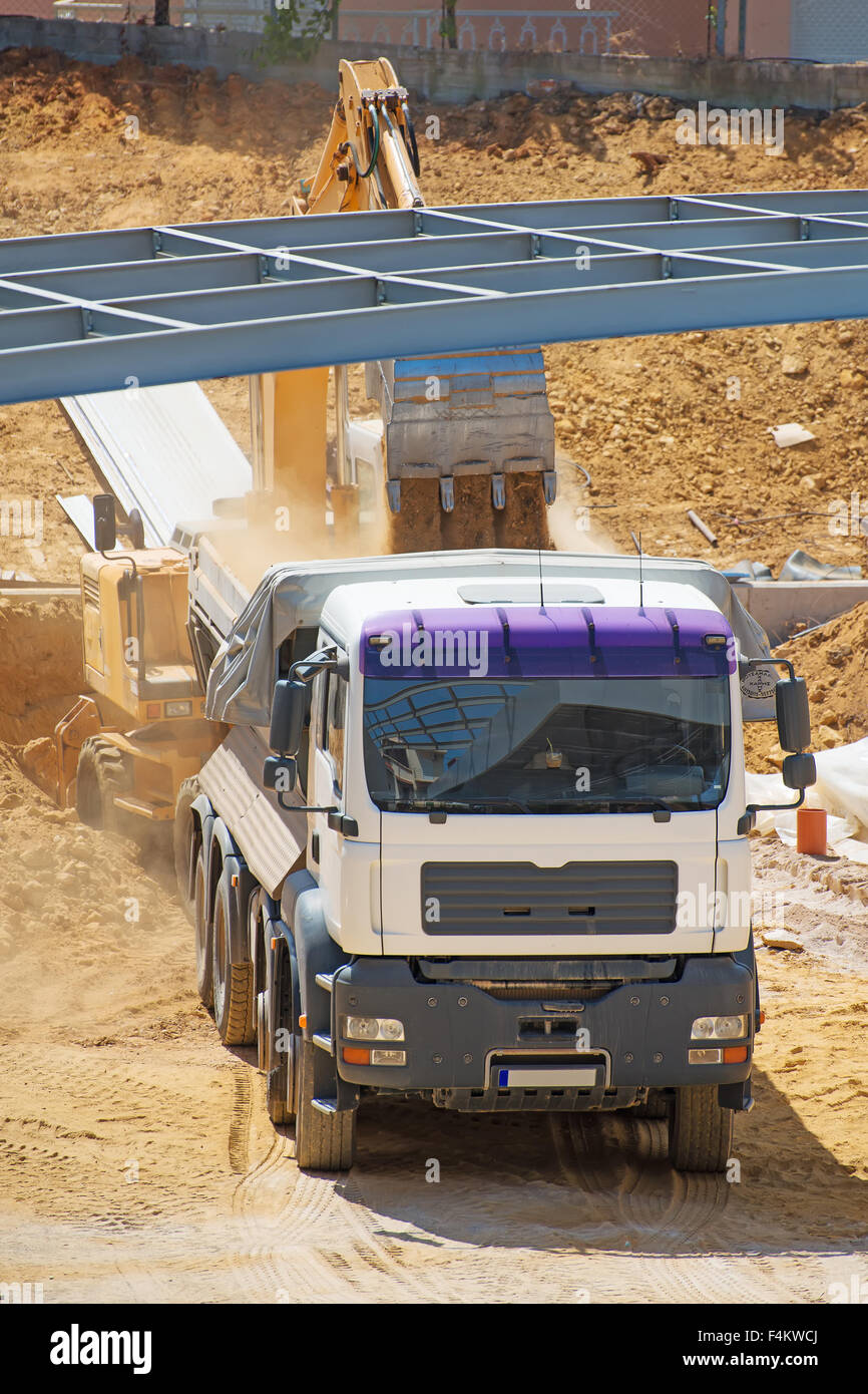 Excavator loading truck on construction site Stock Photo - Alamy