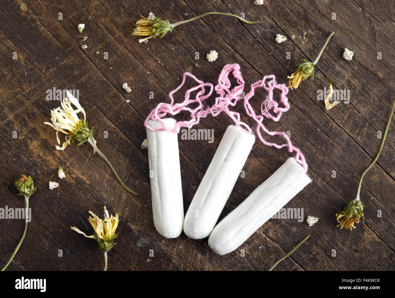 Clean white tampons lying on wooden surface with yellow colored dry ...