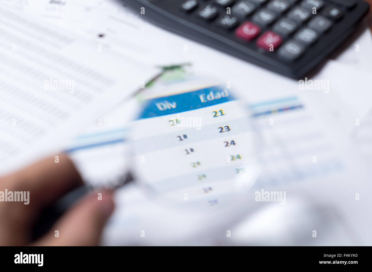 Closeup magnifying glass over paper with numbers and calculator sitting ...