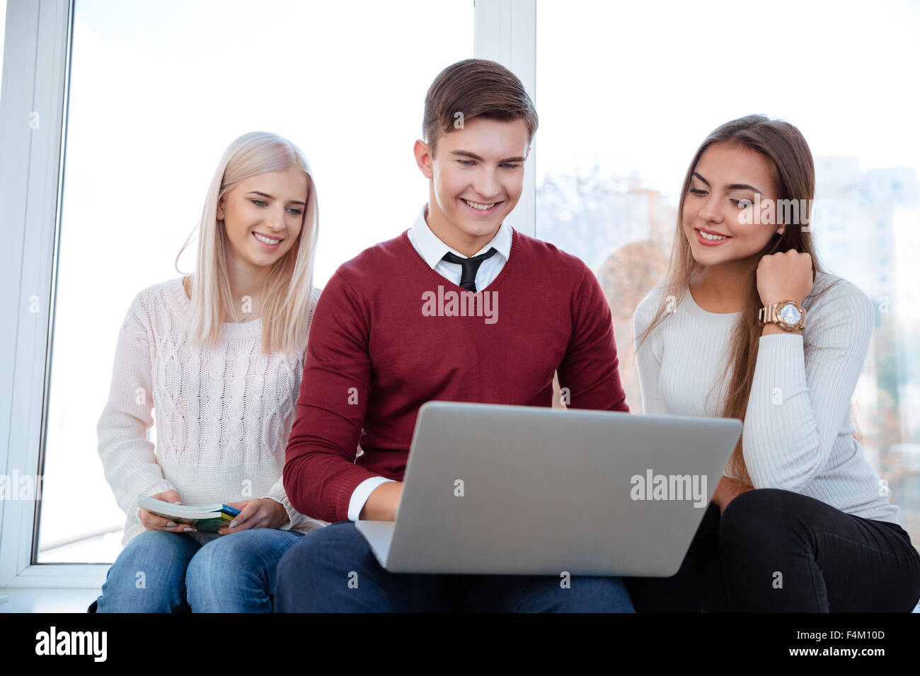 Portrait of a happy students using laptop computer together in ...