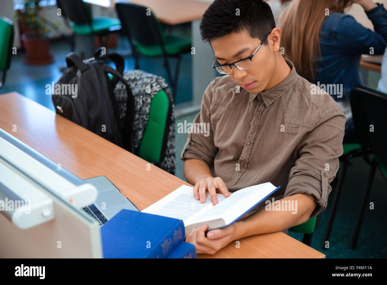 Portrait of a male student reading book in classroom Stock Photo - Alamy