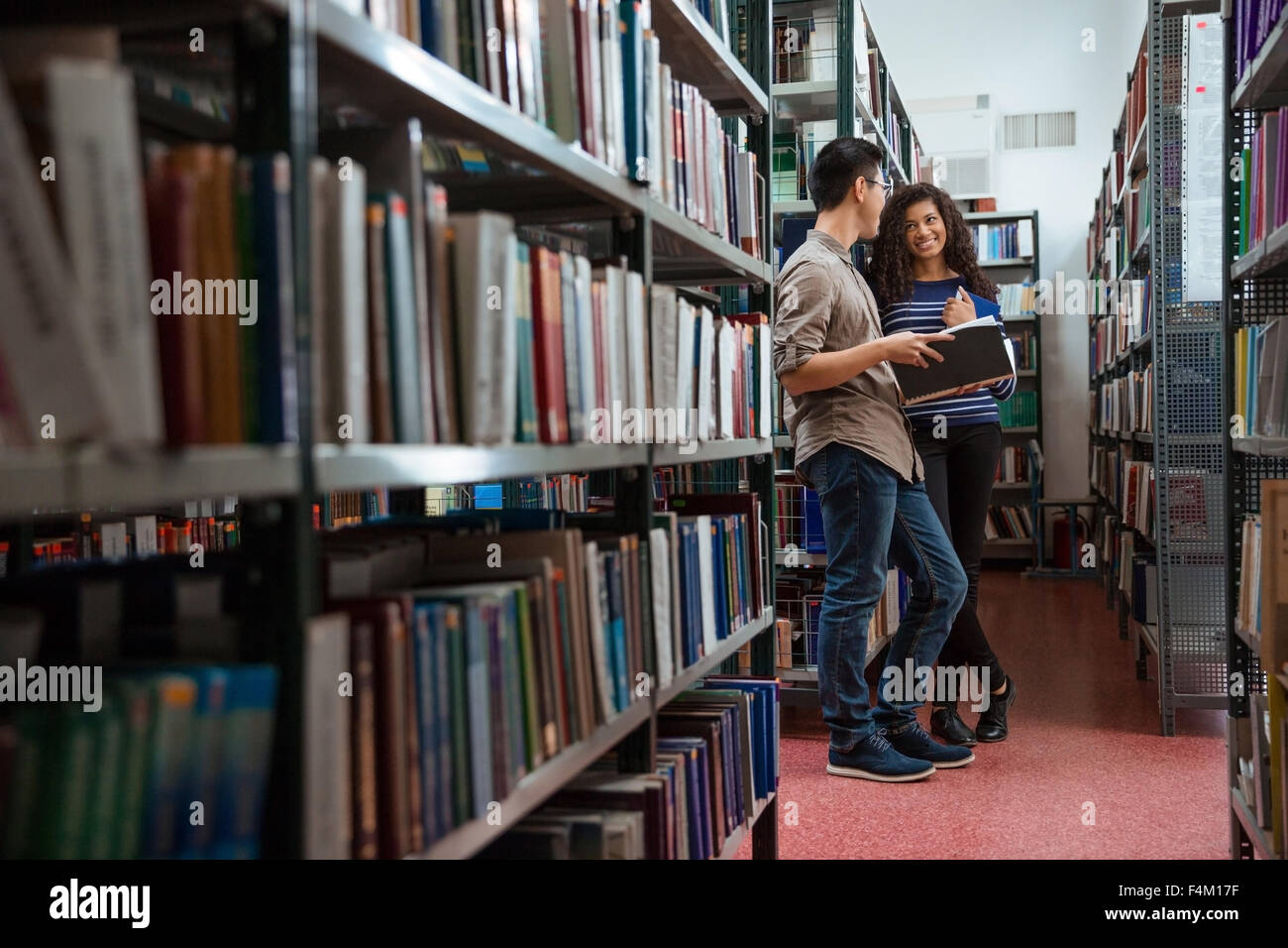 Portrait of a happy students talking in library Stock Photo - Alamy