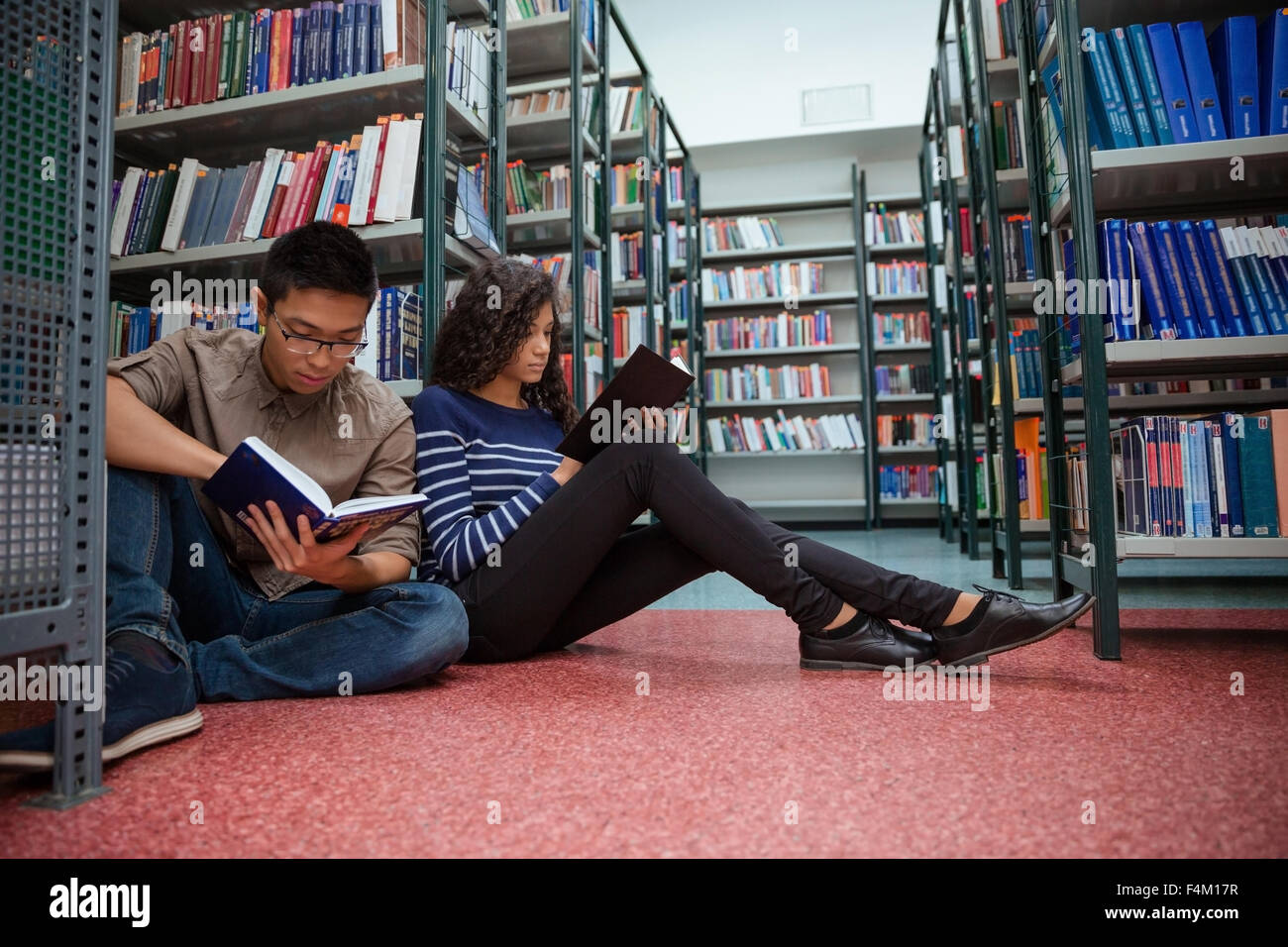 Portrait of a students sitting on the floor and reading books in ...
