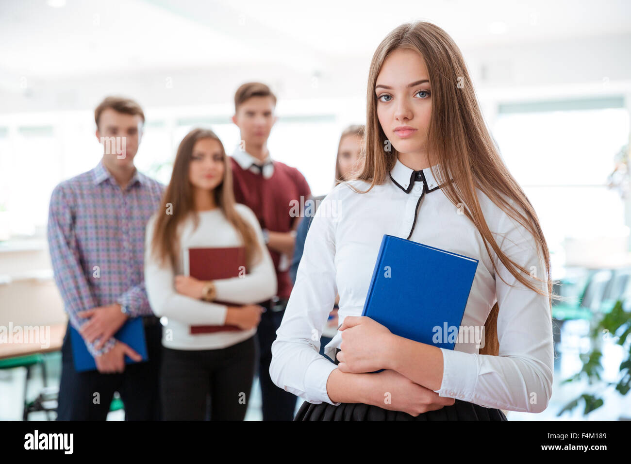 Portrait of a beautiful female student standing with classmates on ...