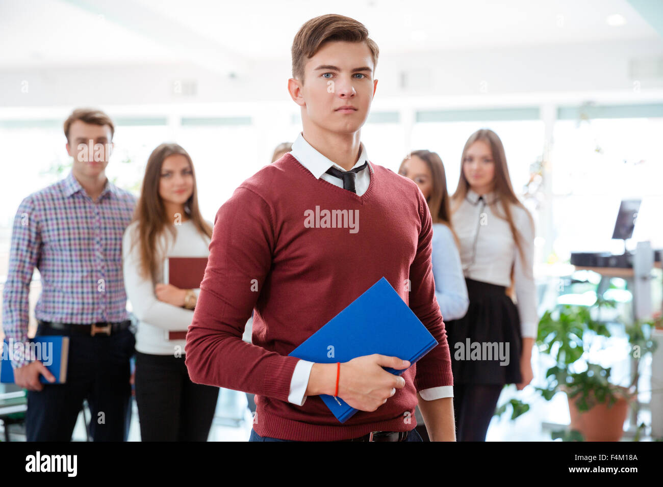 Portrait of a handsome male student standing in classroom with ...