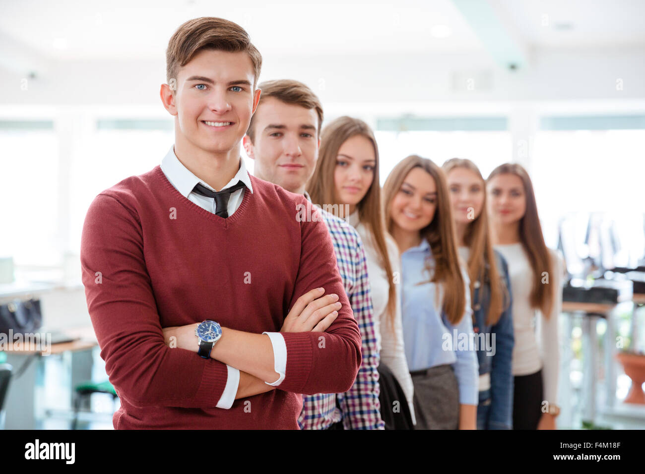 Portrait of a smiling student standing in a line at university and ...