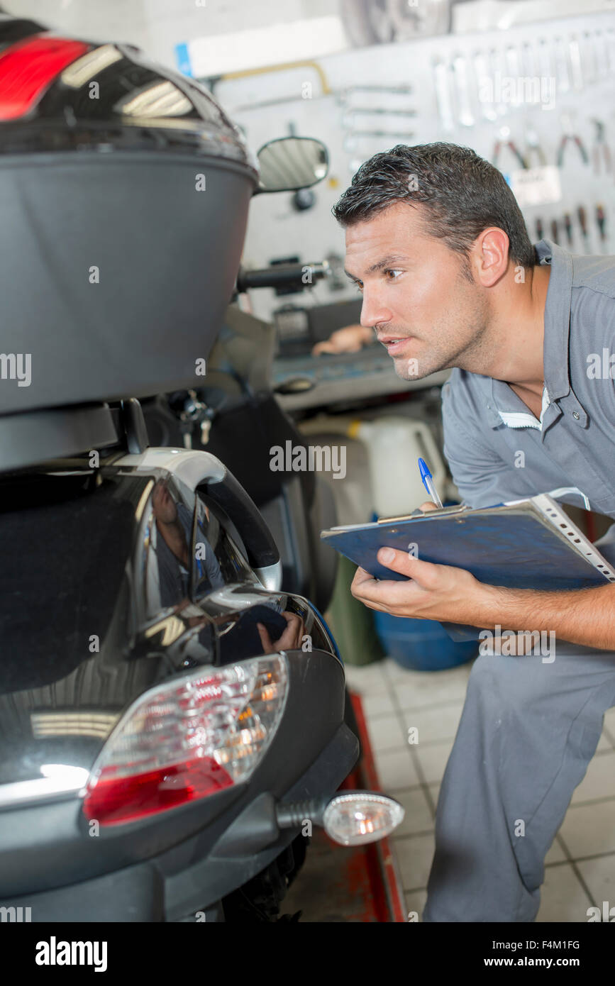 Mechanic assessing a broken scooter Stock Photo - Alamy