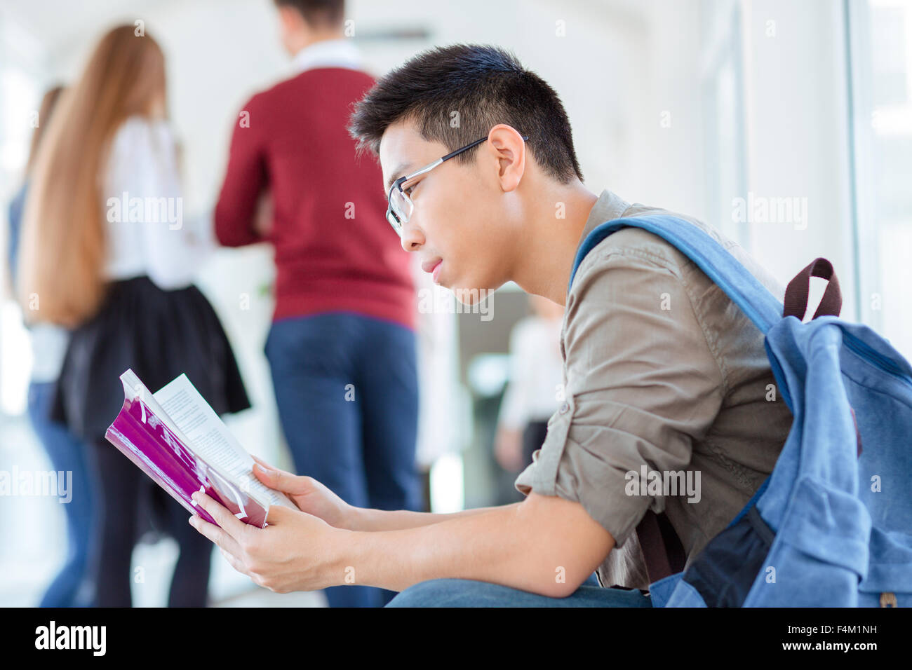 Portrait of a young male student reading book in university hall Stock ...
