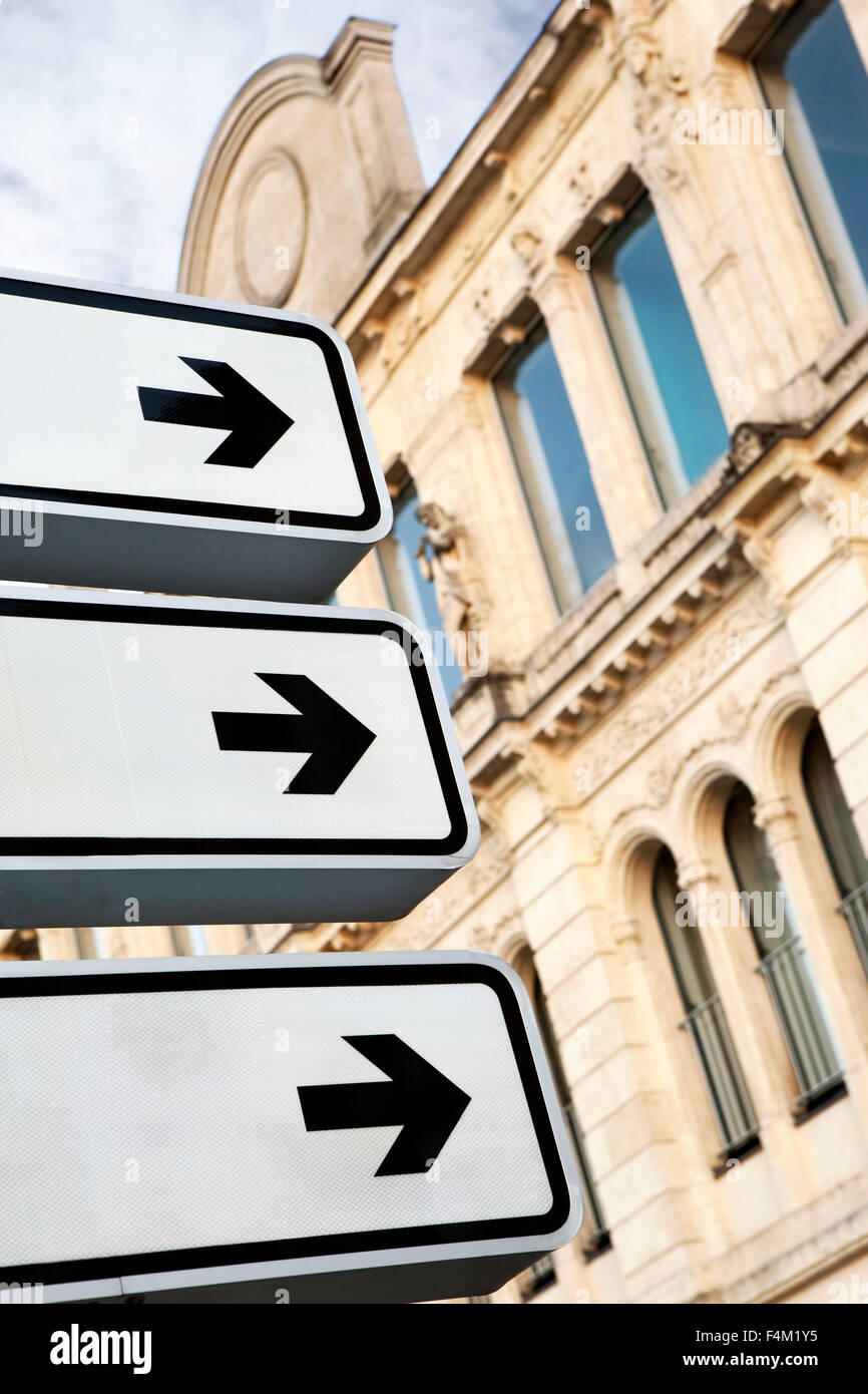 Arrows on road signs facing a stone building Stock Photo - Alamy