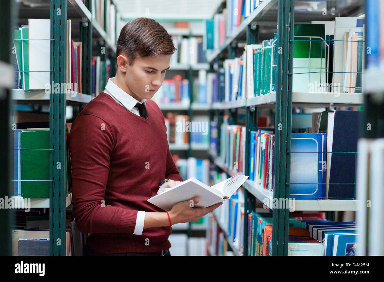 Portrait of a young female student searching book in university library ...