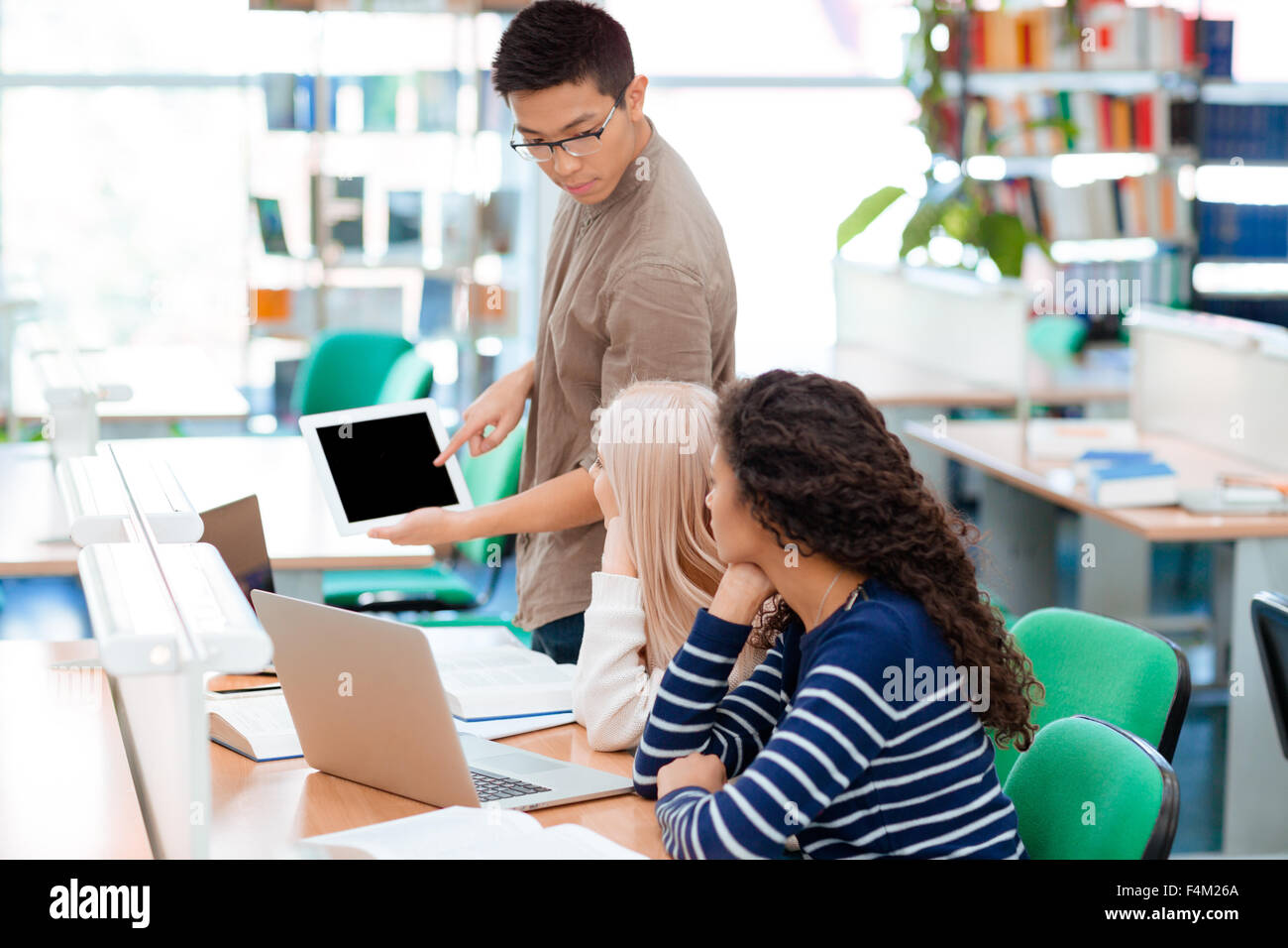 Portrait of a male student showing something on blank tablet computer ...