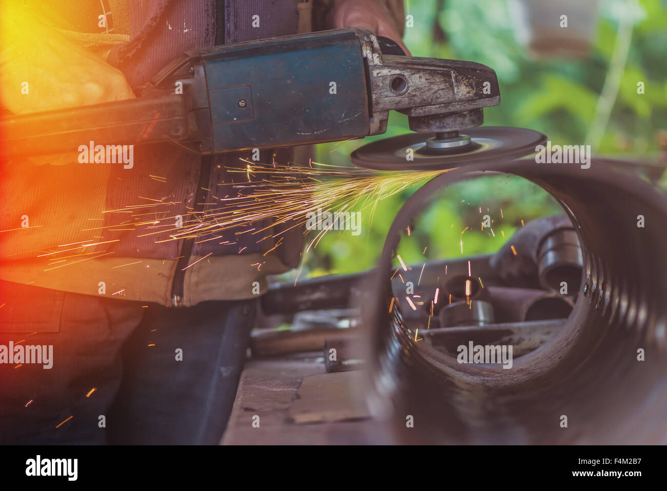 Worker grinding steel pipe, man using grinder to work on piece of metal ...