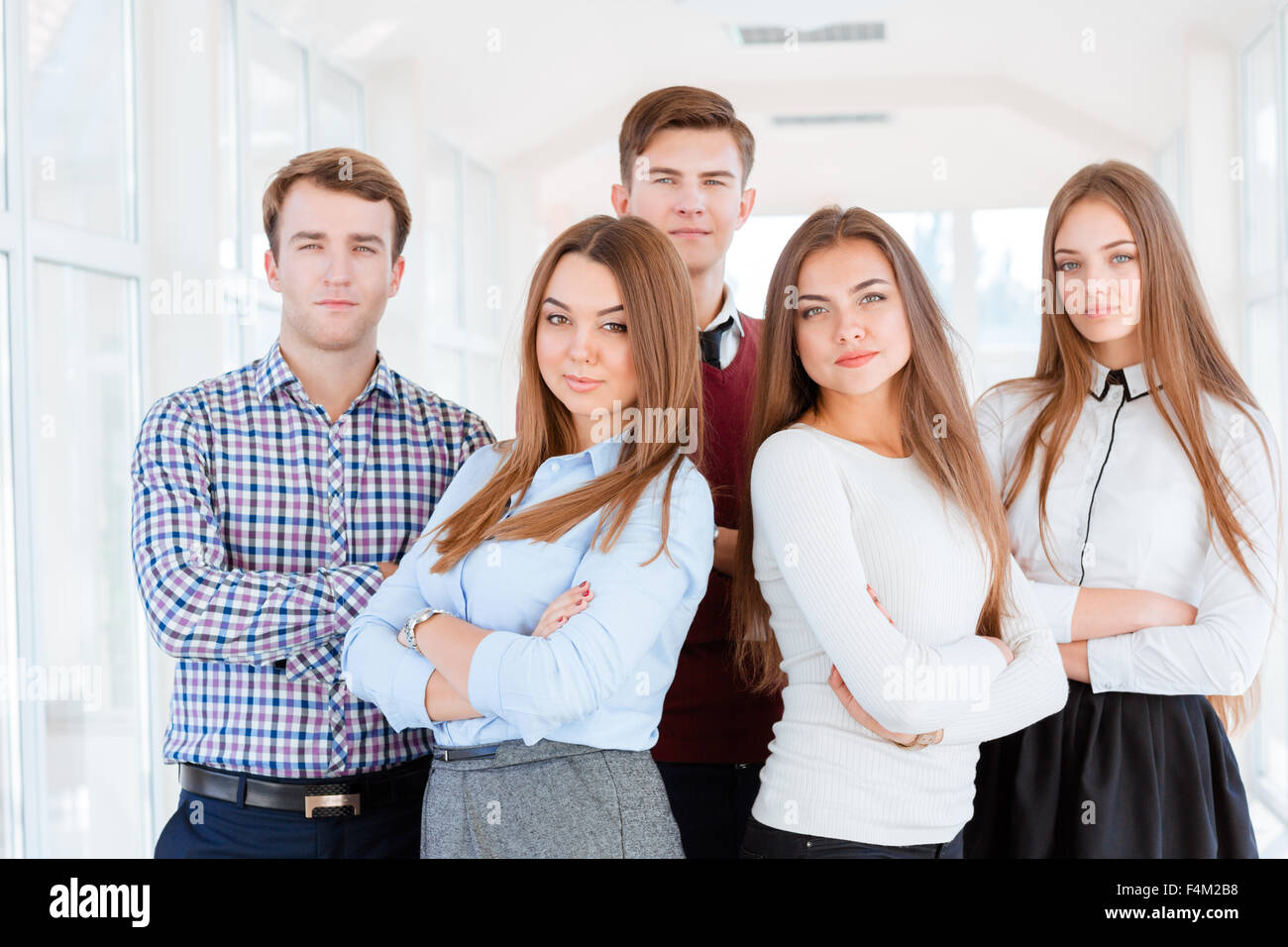 Group of a students standing in university hall and looking at camera ...